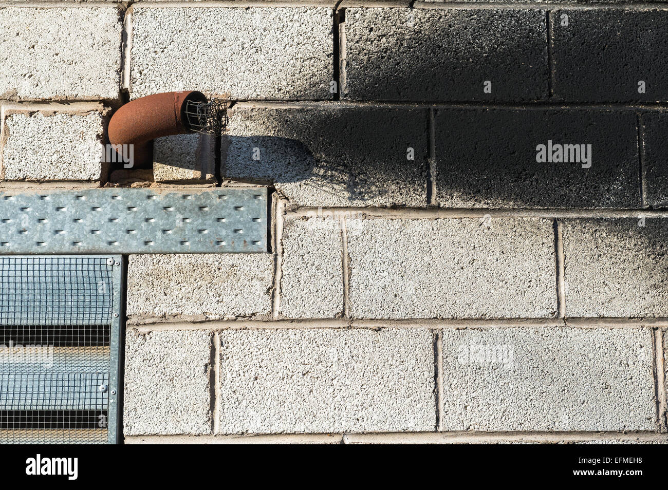 Metal exhaust pipe coming from a block built building with soot stains ...