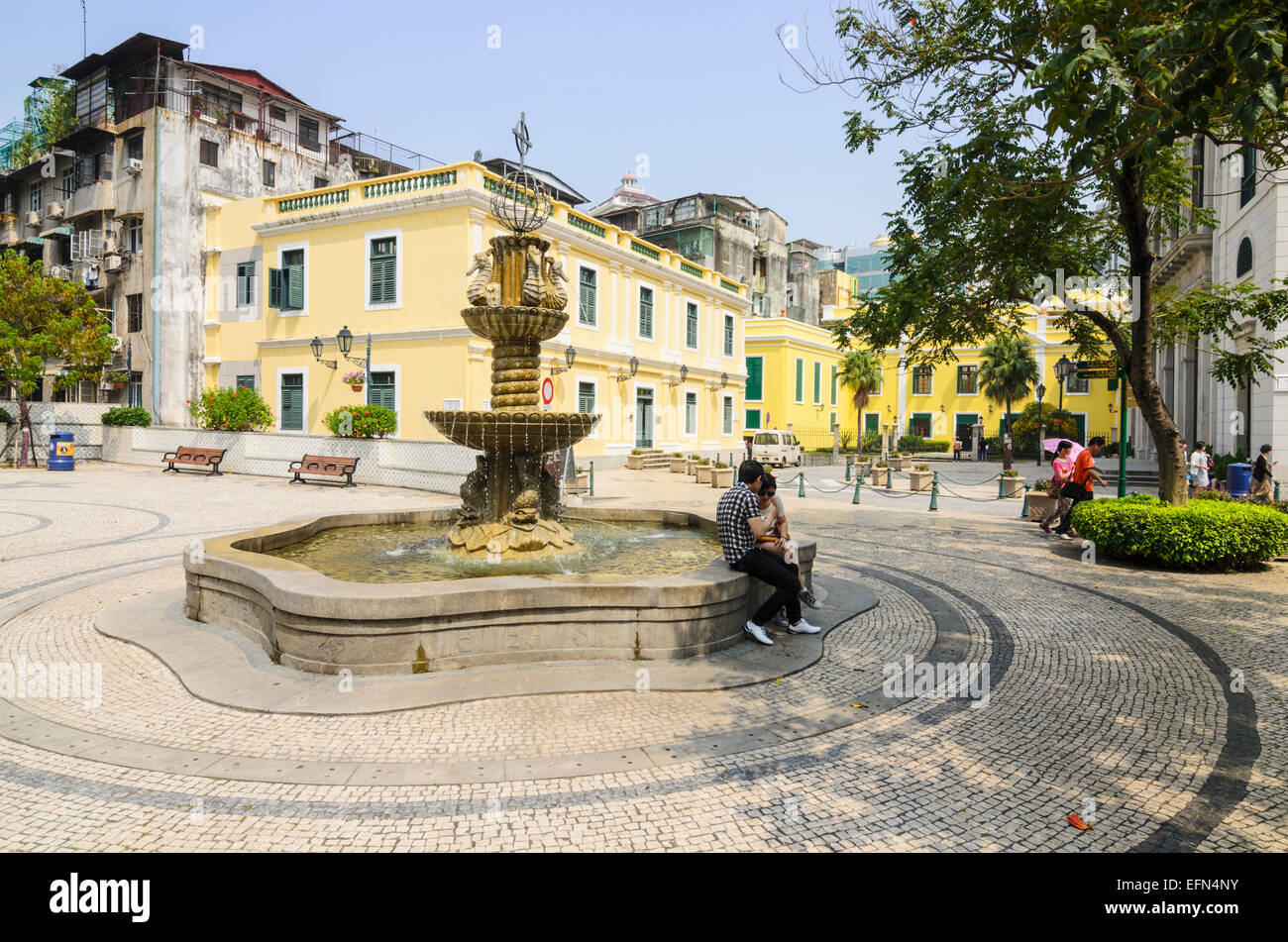 People seated on the wall of a fountain in Cathedral Square, Macau ...
