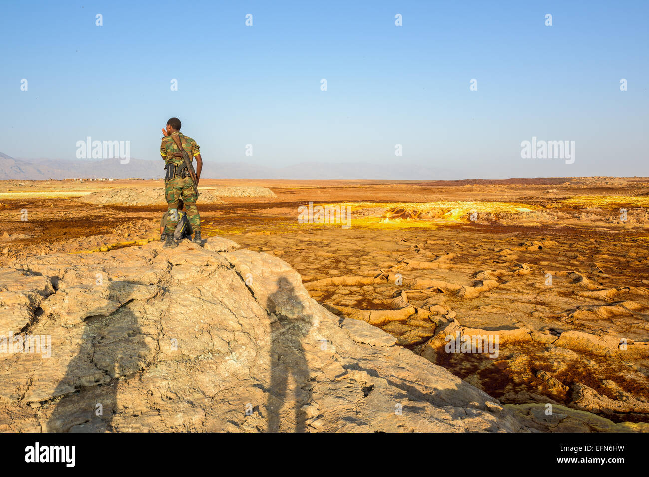 Sulfuric acid pools in Dallol in Ethiopia with a guard standing on a ...