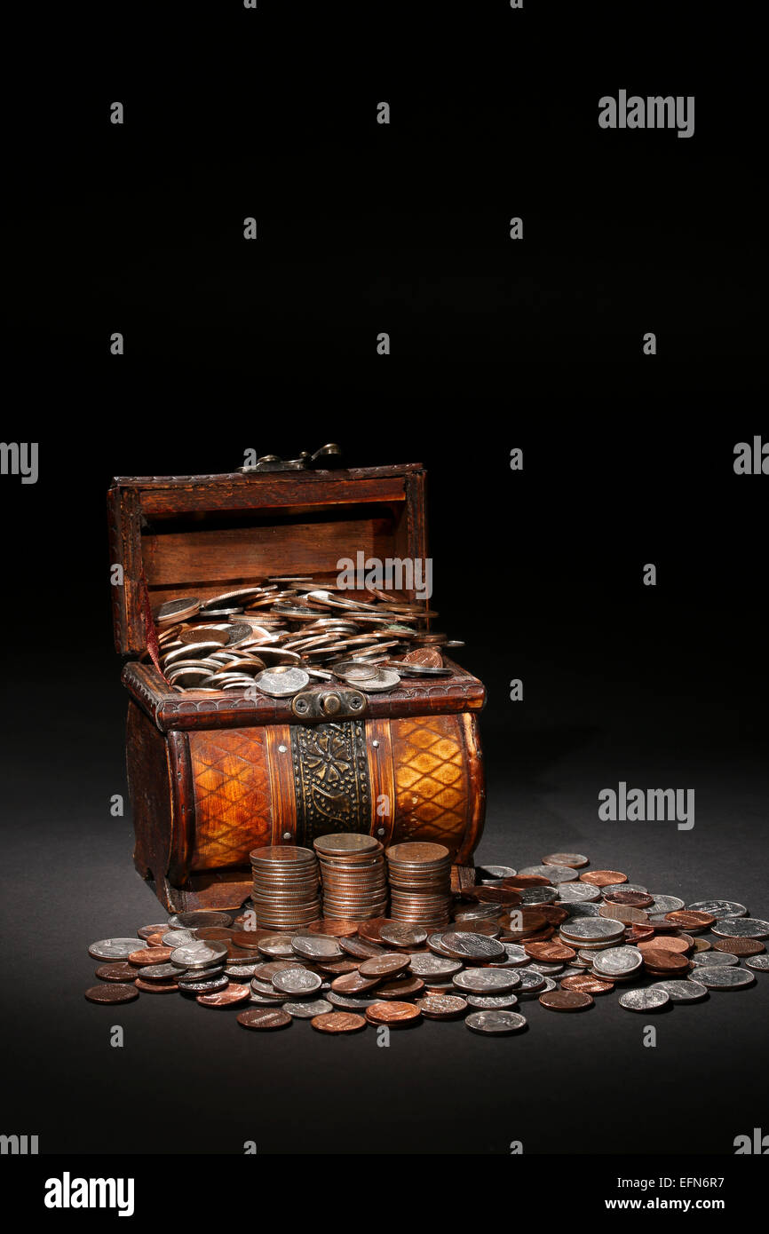 Small treasure chest full of loose change with coins on the table ...