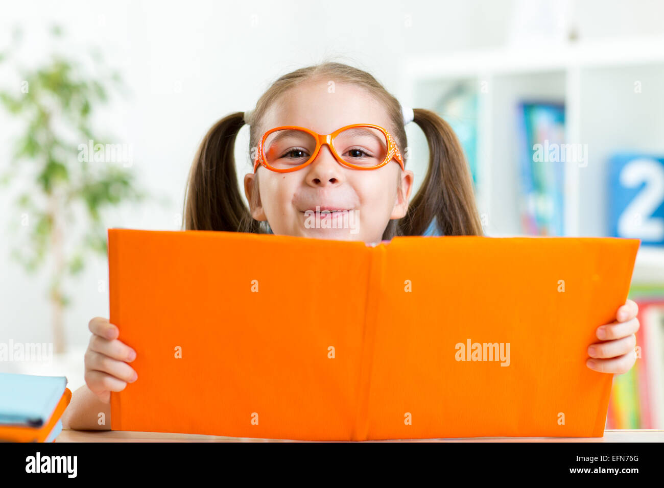 clever child little girl behind of open book indoor Stock Photo - Alamy