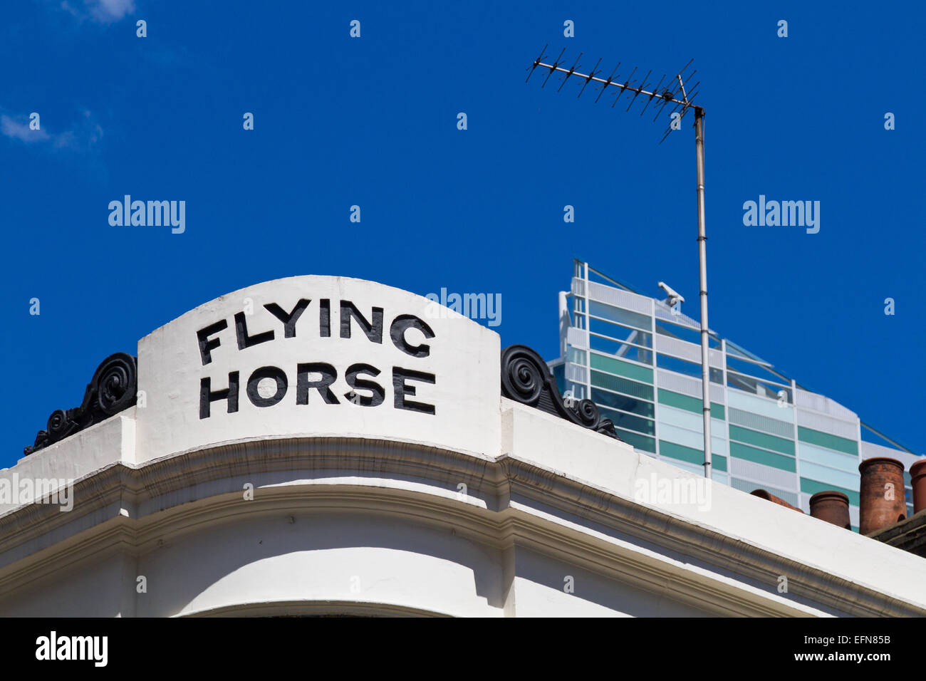 Sign showing Flying Horse pub with tv aerial and glass building behind ...