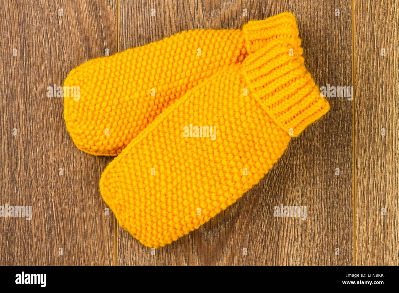 yellow knitting mittens on wooden background Stock Photo - Alamy
