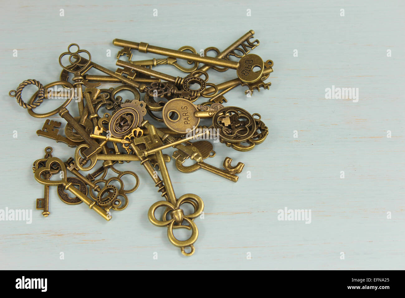 Pile of antique brass keys on a pale green distressed wood background ...