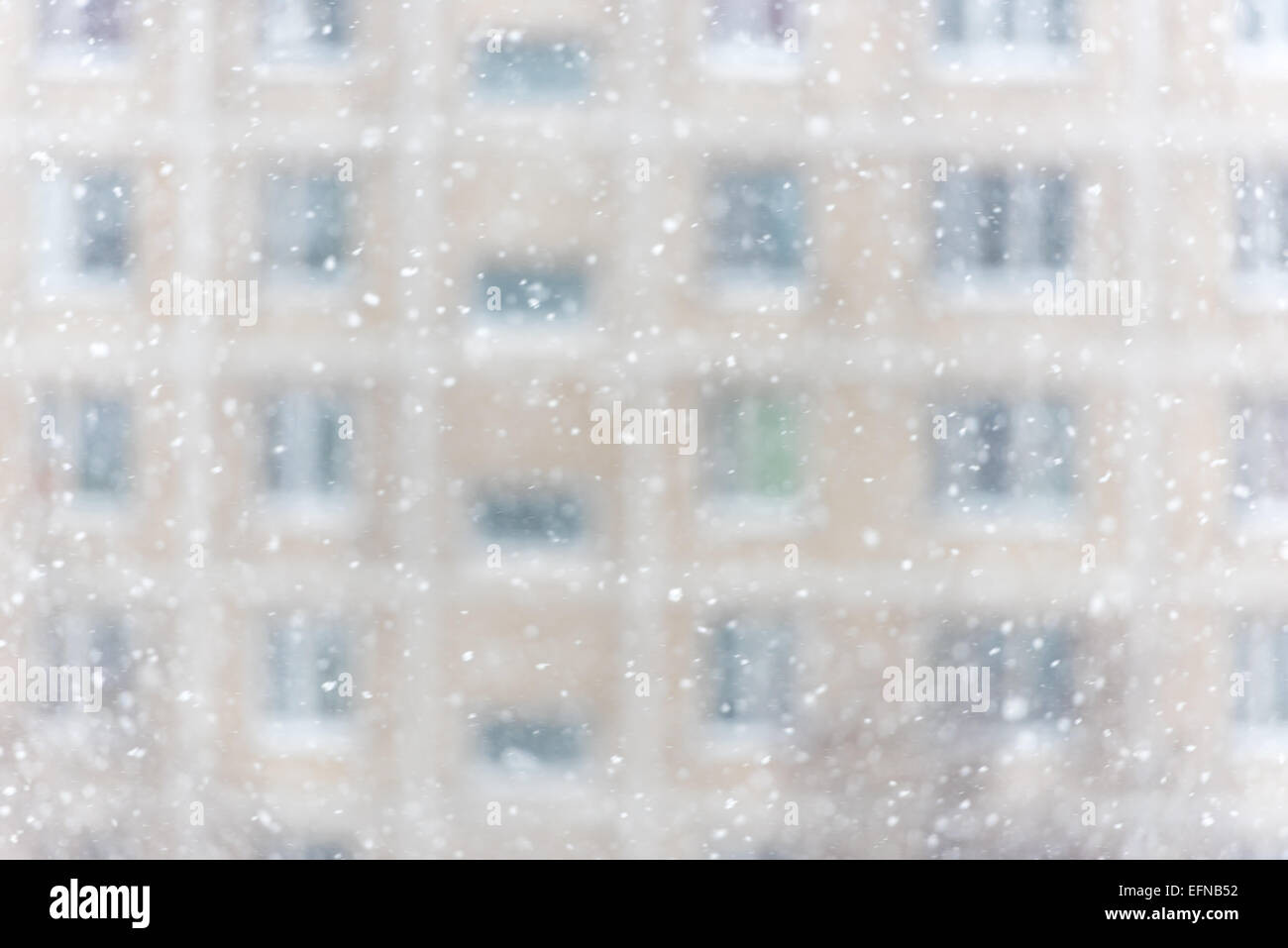 Snowfall on a residential building facade. Winter blur background with ...