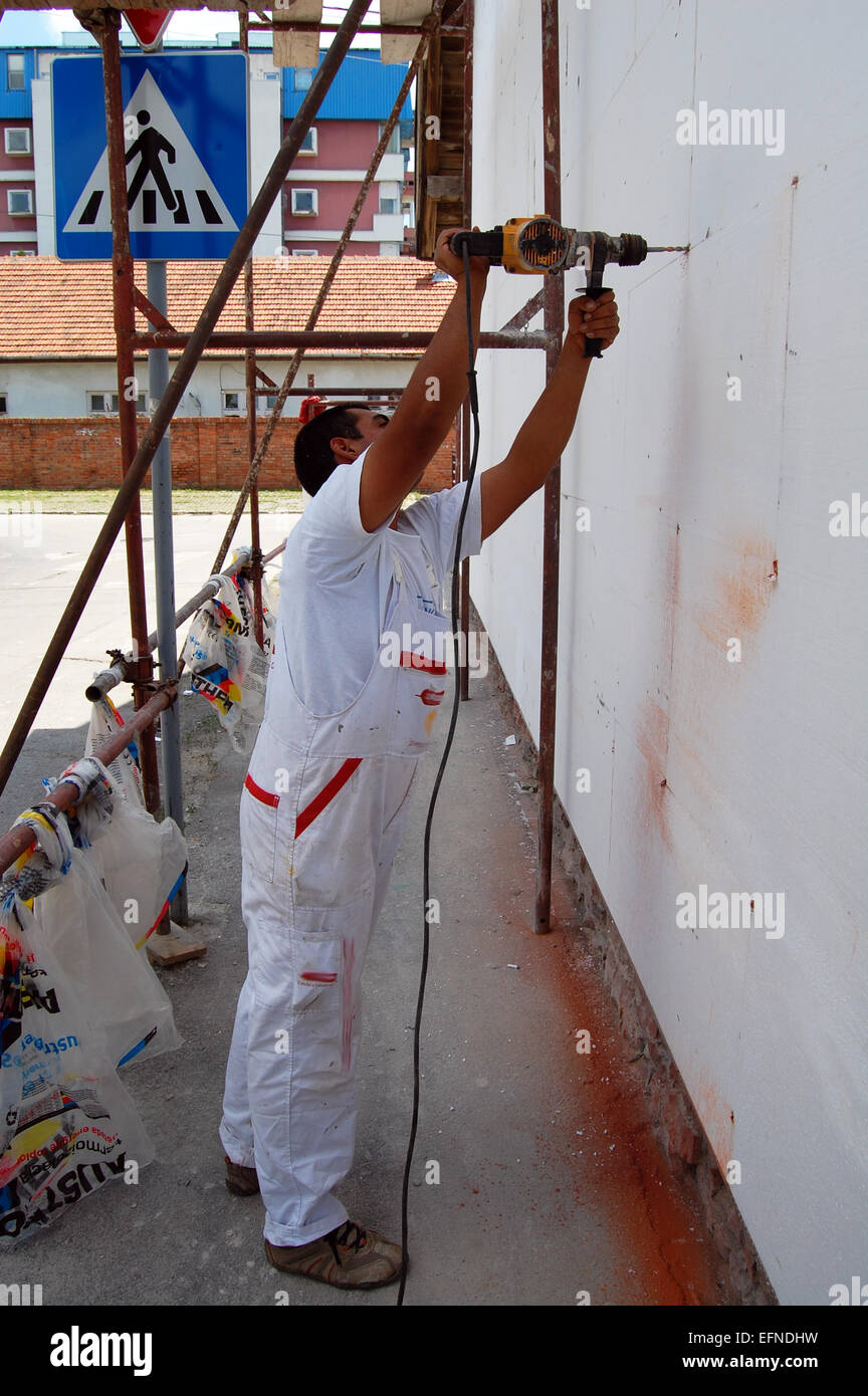 Young master drilled facade wall works fixing styrofoam protection ...