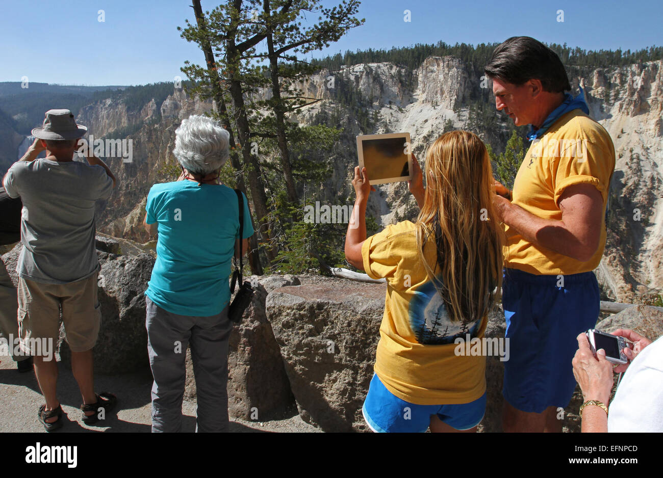Visitors are seen photographing the Lower Falls of the Yellowstone ...