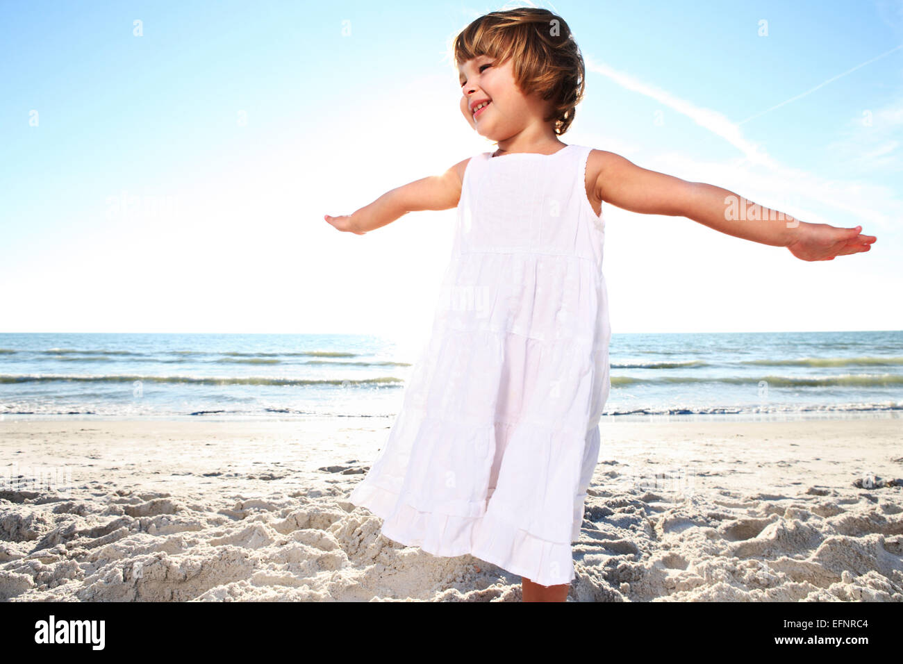 Small cute girl in white dress enjoying sunny day at the beach. Shoot ...