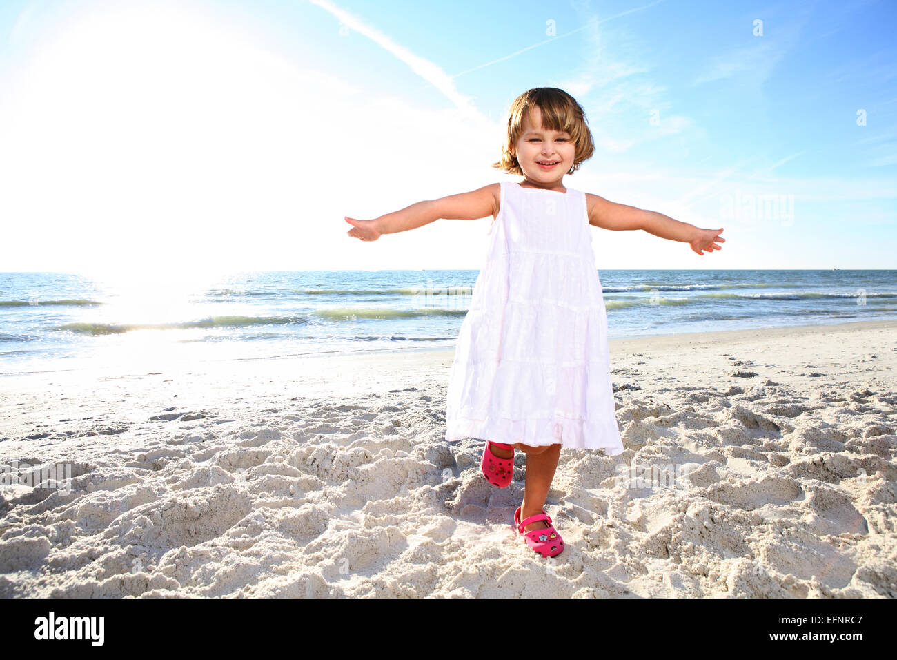 Small happy girl in white dress enjoying sunny day at the beach. Shoot ...