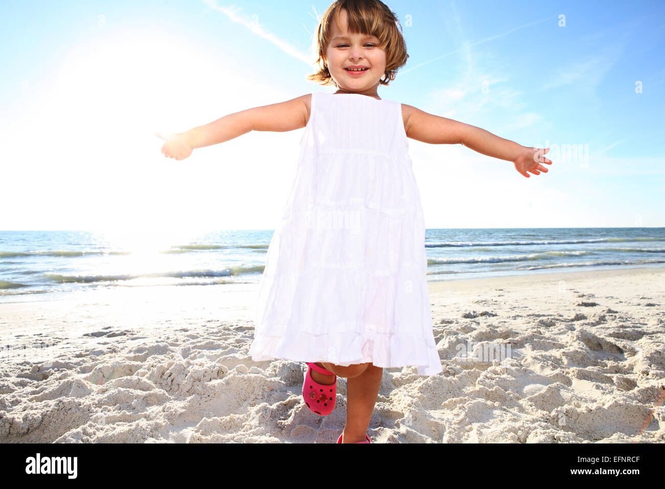 Happy little girl in white dress enjoying sunny day at the beach. Shoot ...