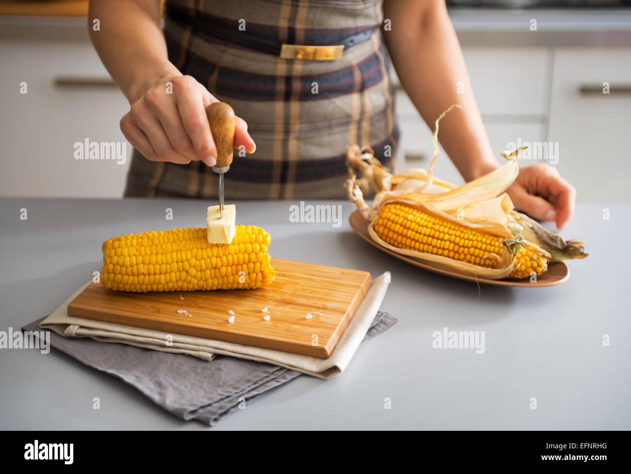 Closeup on young housewife rubbing boiled corn with butter Stock Photo ...