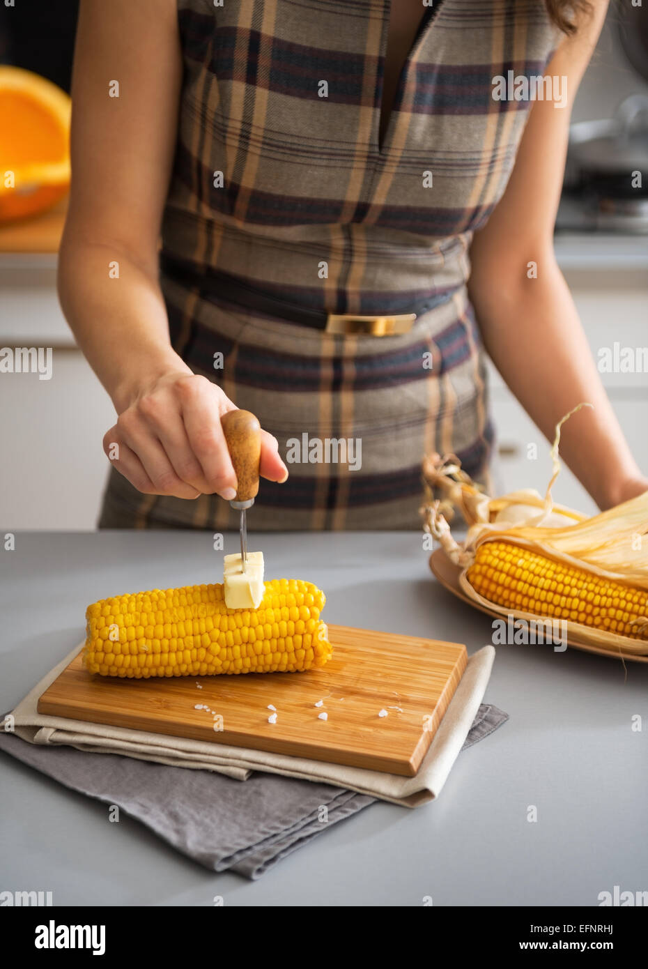Closeup on young housewife rubbing boiled corn with butter Stock Photo ...