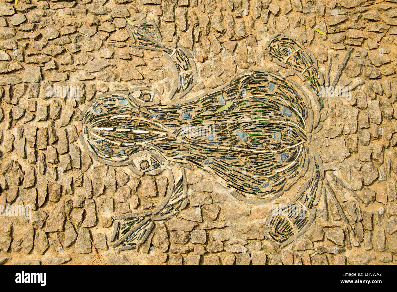 A frog created in the pavement out of small stones and pebbles, in the ...
