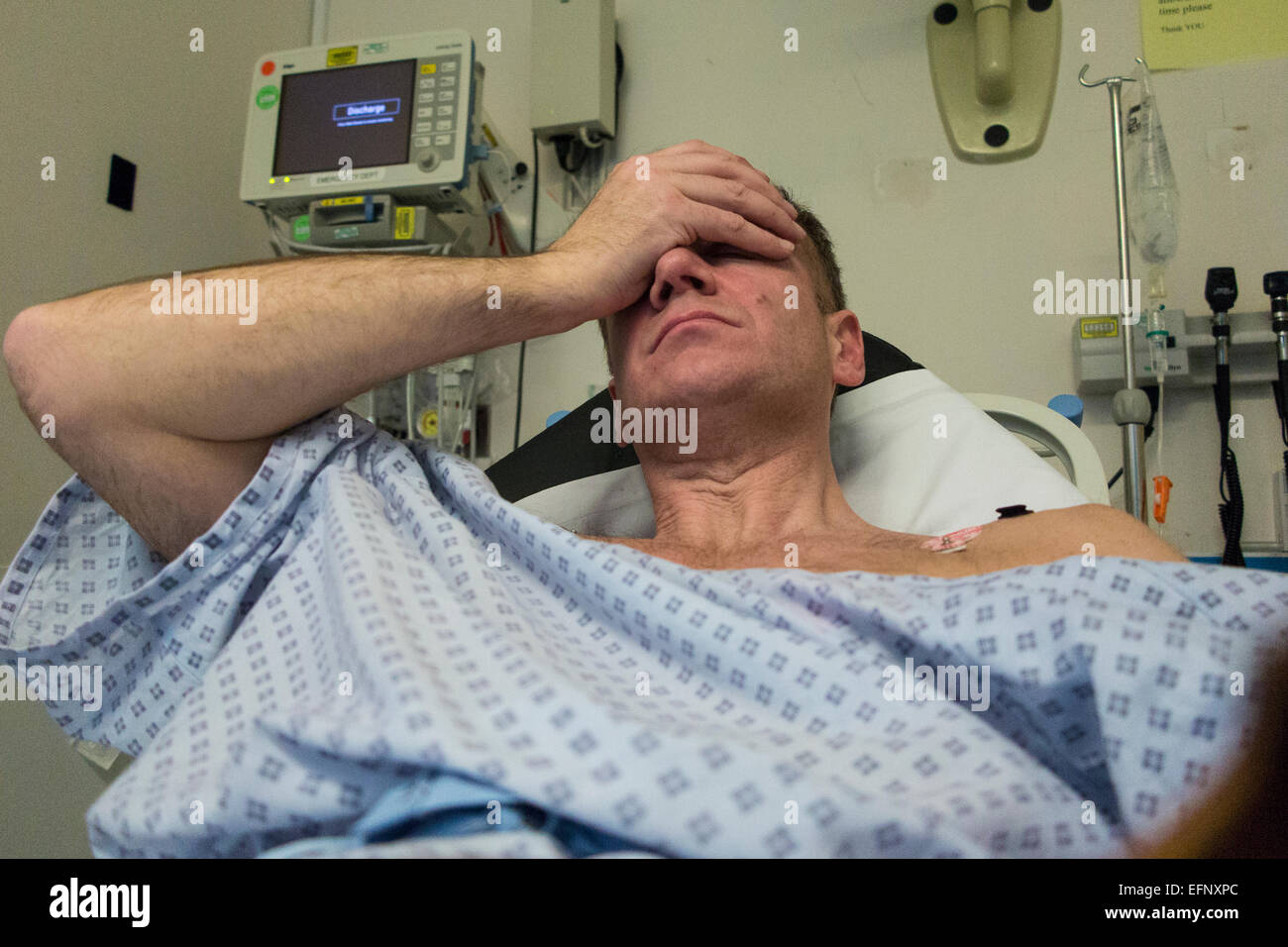 An ill man in hospital attached to a heart monitor with a drip attached ...