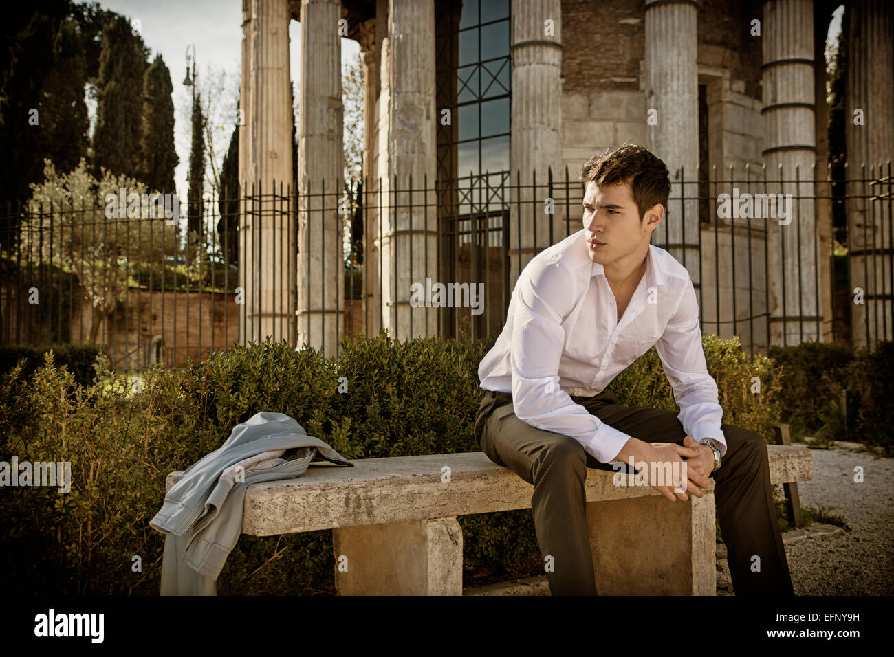 Handsome young man in European city, sitting on stone bench Stock Photo ...