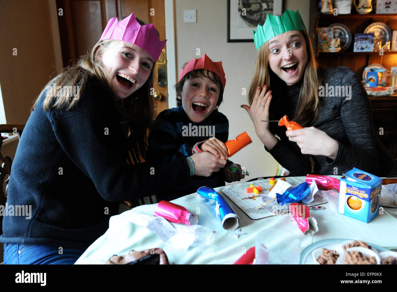 Three young cousins pulling crackers at the Christmas dinner table ...