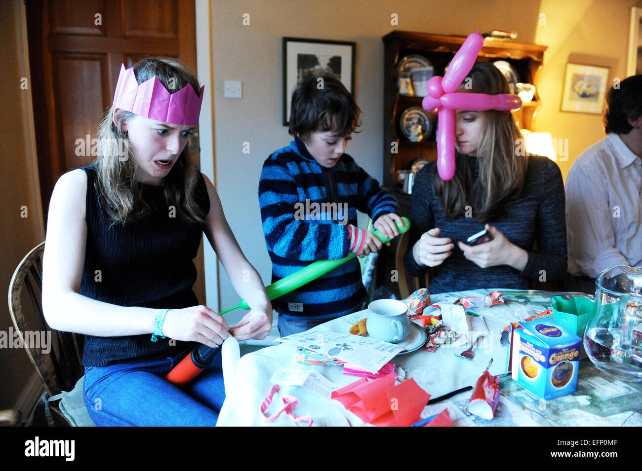 Three young cousins pulling crackers at the Christmas dinner table ...