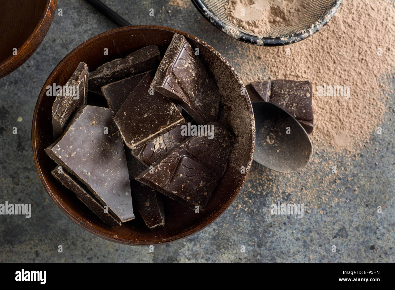 dark chocolate chunks in wooden bowl, on oak table Stock Photo - Alamy