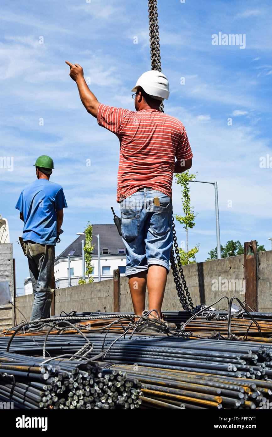 Construction workers unloading a truck with iron rods Stock Photo - Alamy