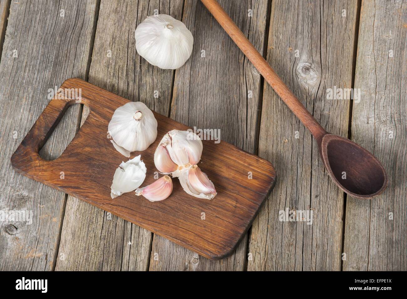 Garlic on old wooden breadboard Stock Photo - Alamy