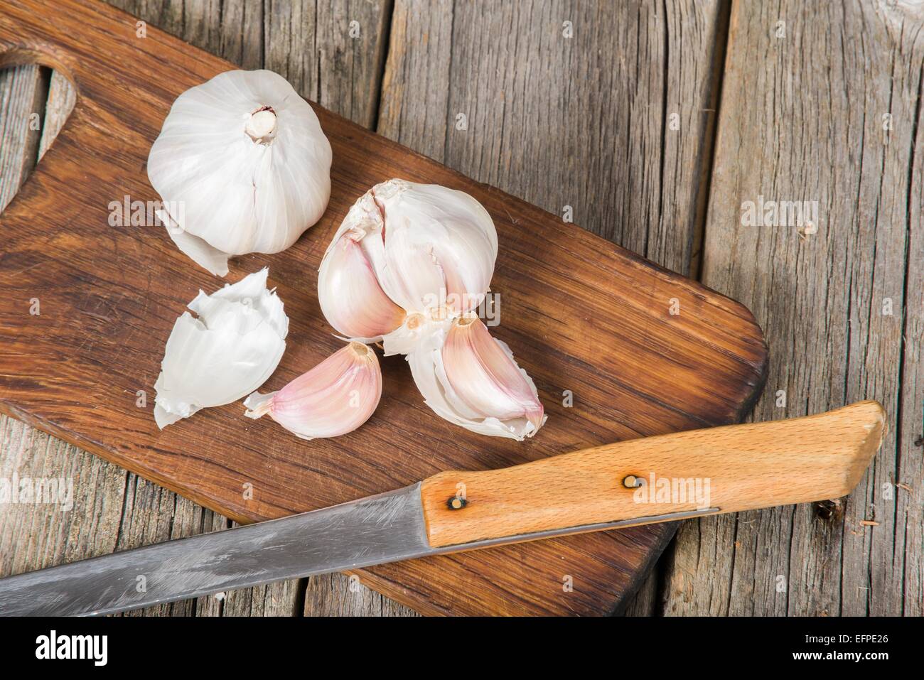 Garlic on old wooden breadboard Stock Photo - Alamy