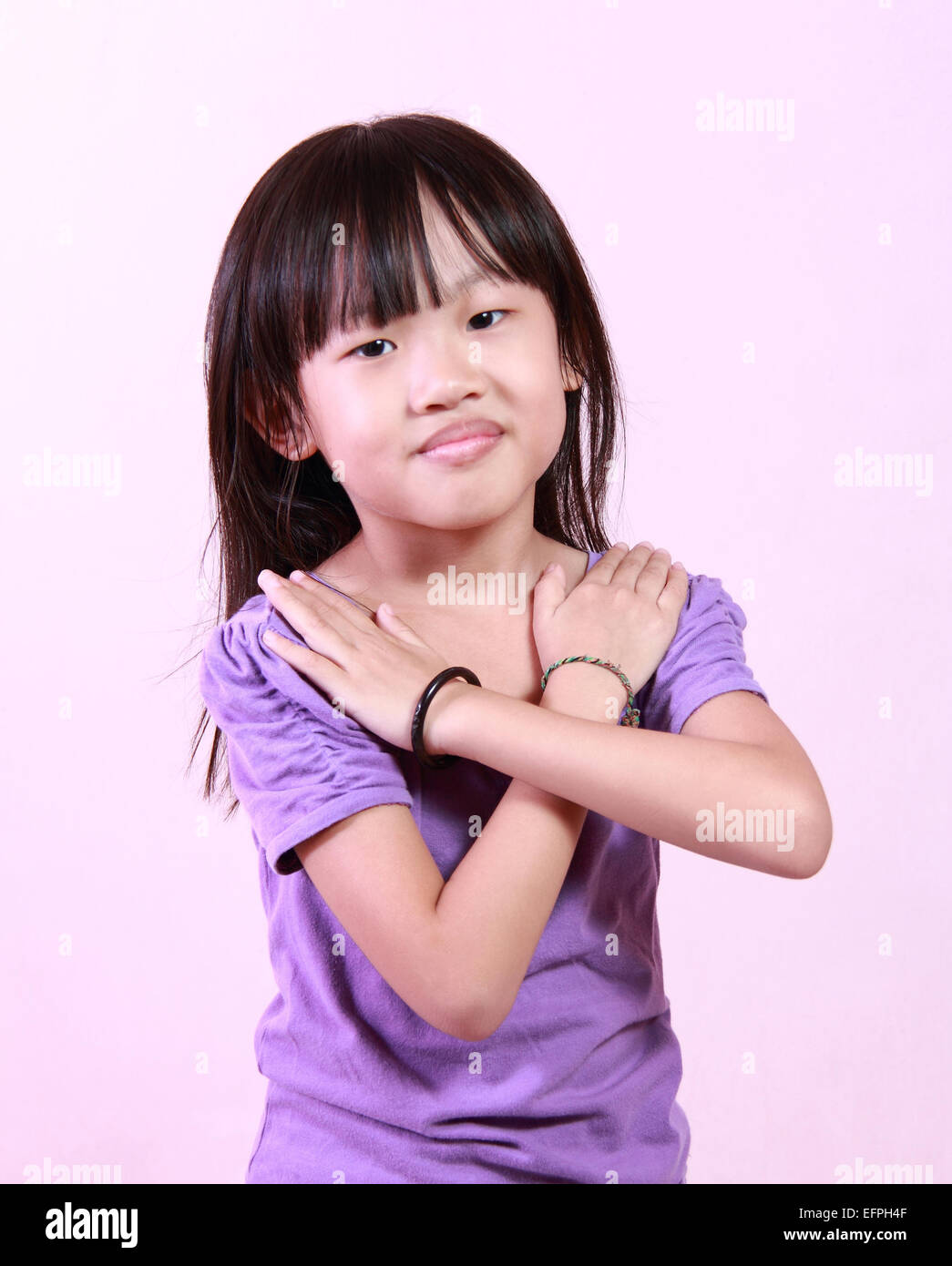 A cute little girl put the hands on chest Stock Photo - Alamy