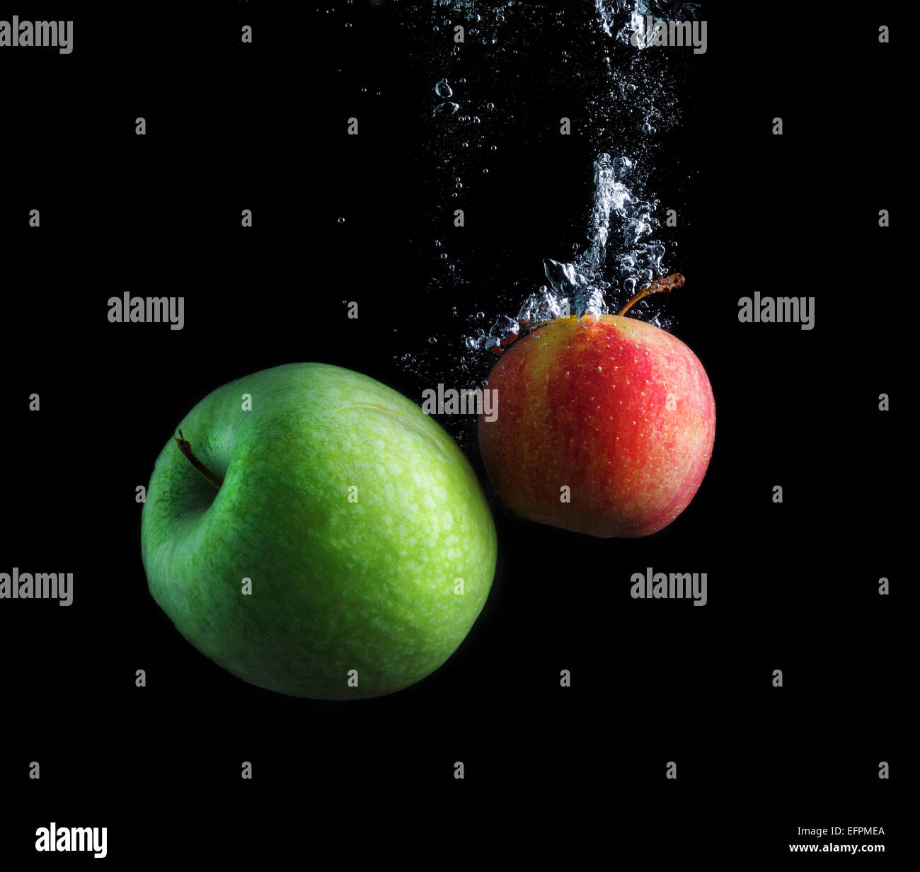 Green and red delicious apples in water with air bubbles on a black ...