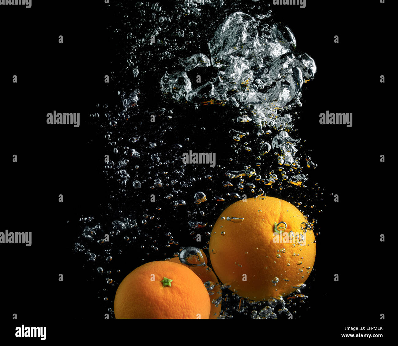 Oranges falling in water with air bubbles on a black background Stock ...