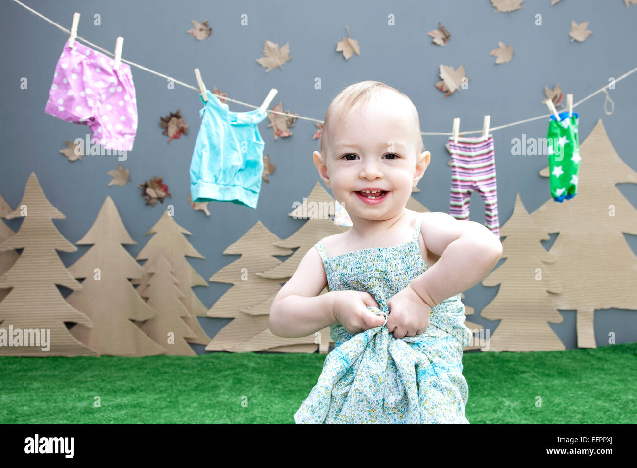 Baby girl with washing line and cardboard leaves Stock Photo - Alamy