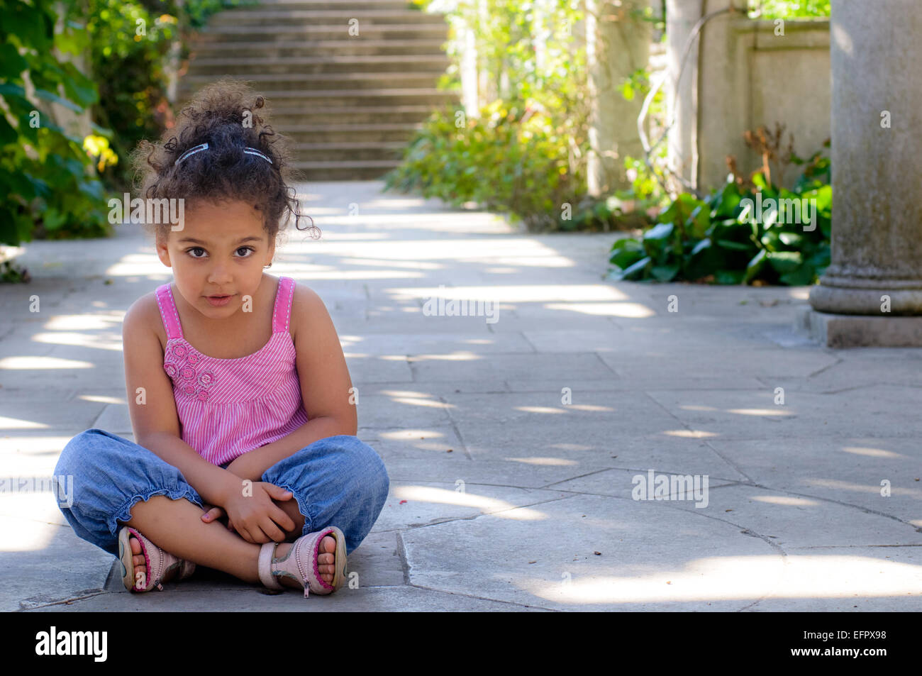 Beautiful little girl sitting with her legs crossed Stock Photo - Alamy