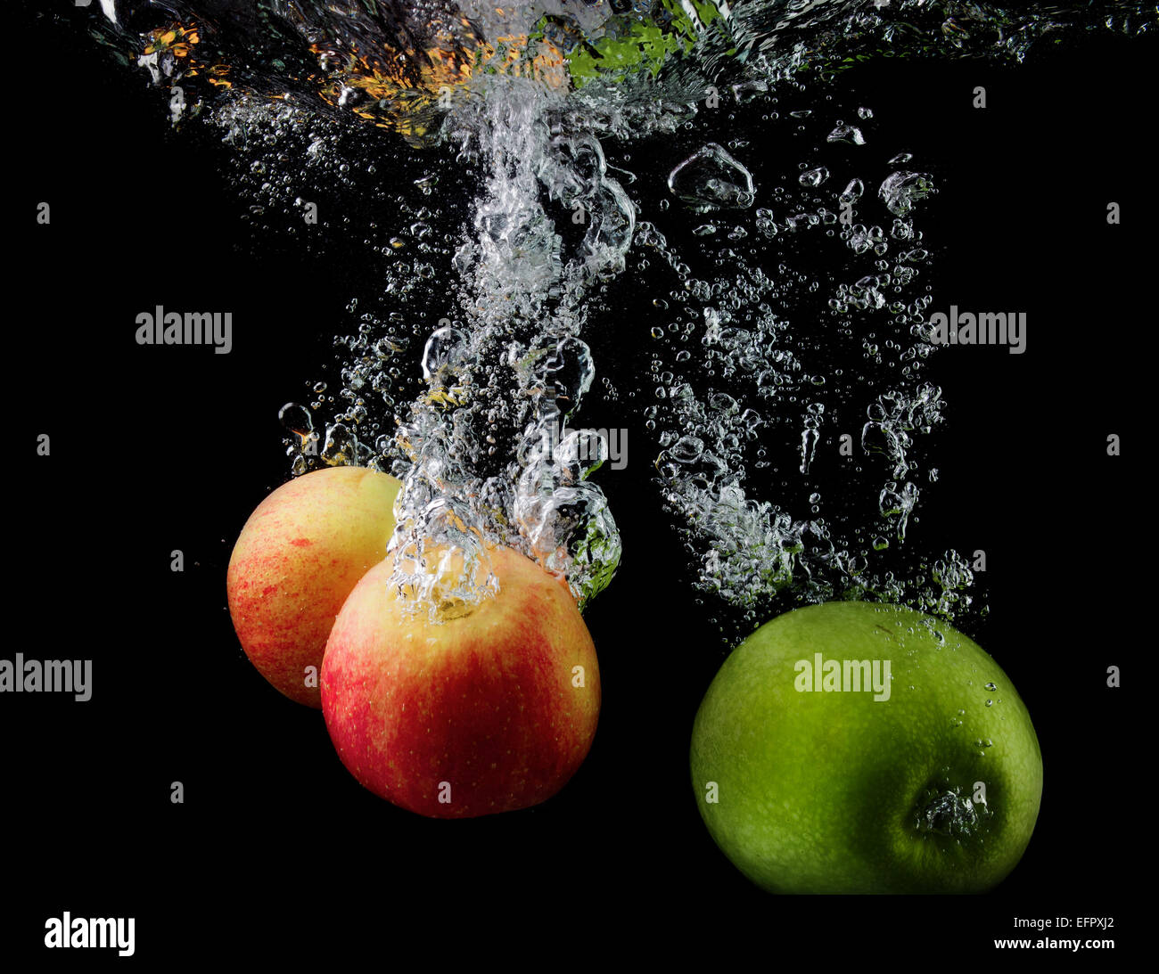 Apples in water with air bubbles on a black background Stock Photo - Alamy