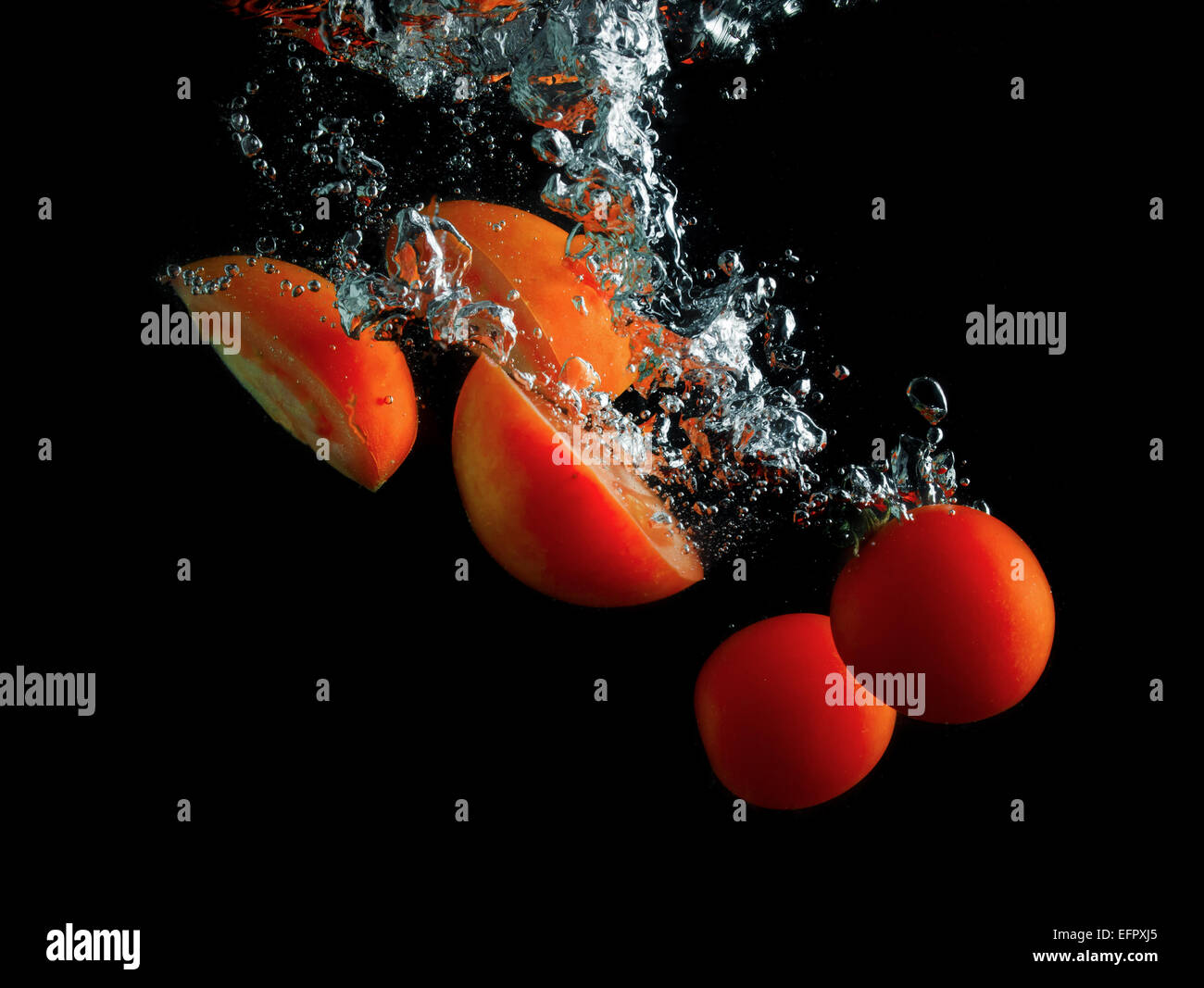Tomatoes falling into the water with air bubbles. Photo on black ...