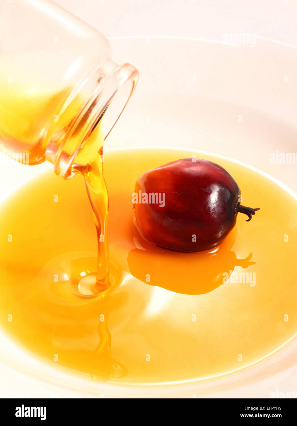 A bottle of palm cooking oil pouring in a white plate Stock Photo - Alamy