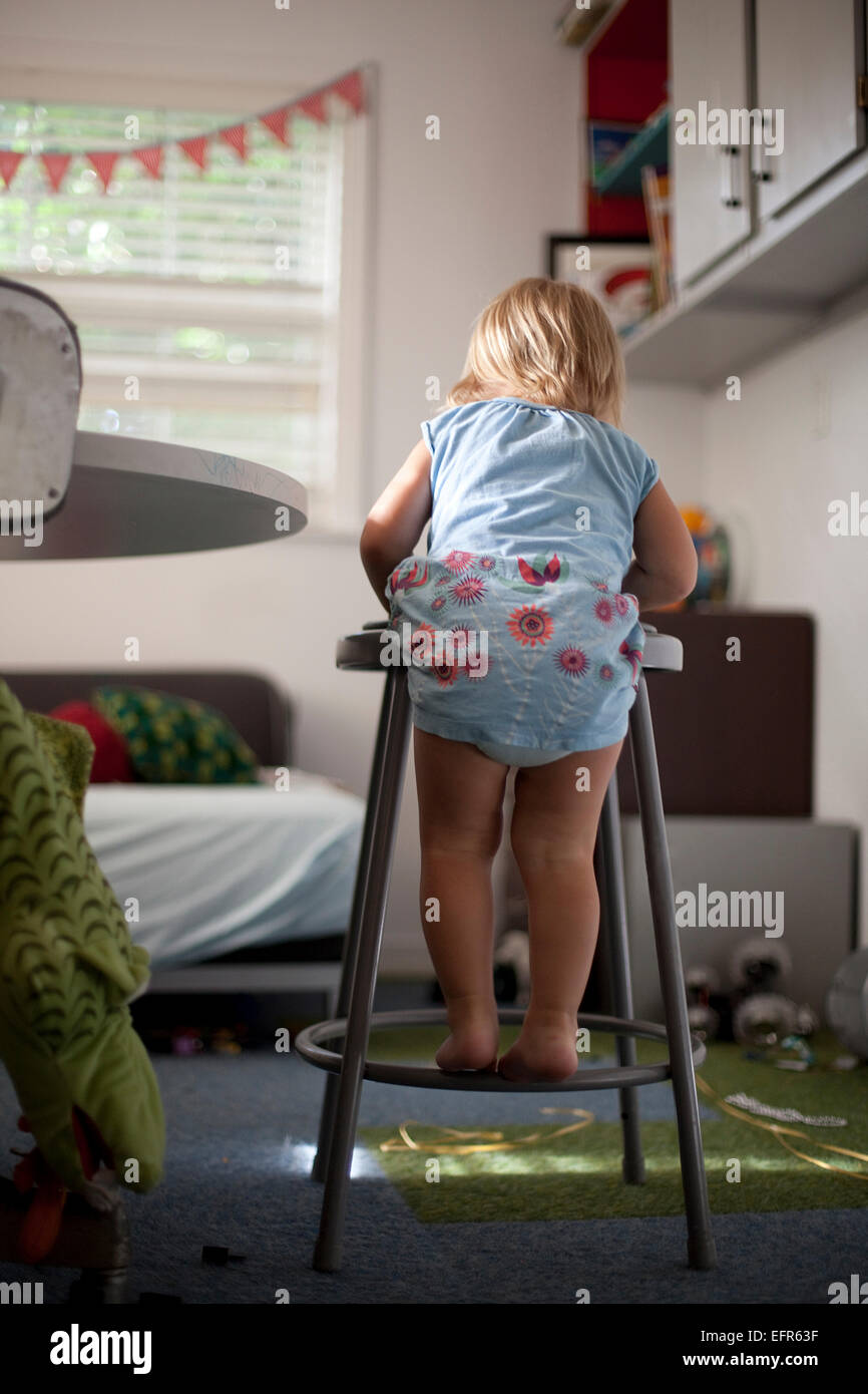 Young girl balancing on stool, rear view Stock Photo - Alamy