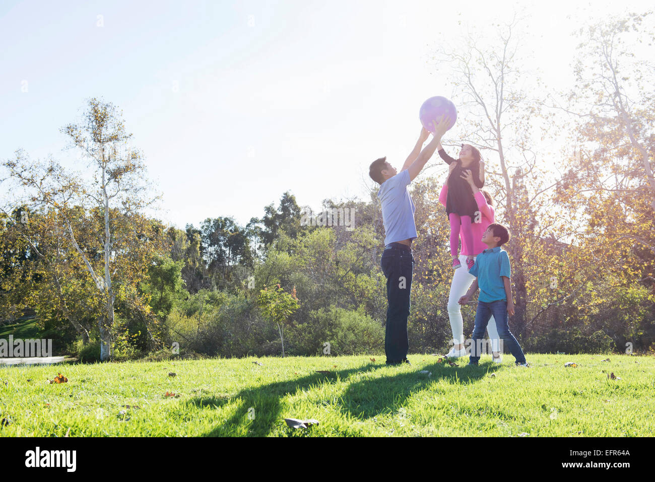 Mature couple and children playing catch with ball in park Stock Photo ...