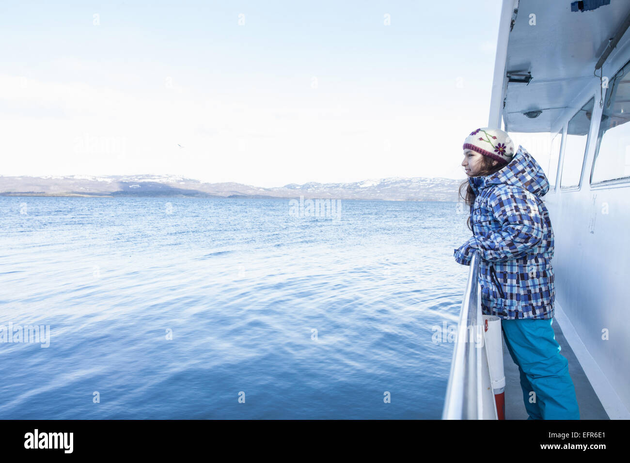 Girl leaning against railing on boat sailing toward coast, Ushuaia ...
