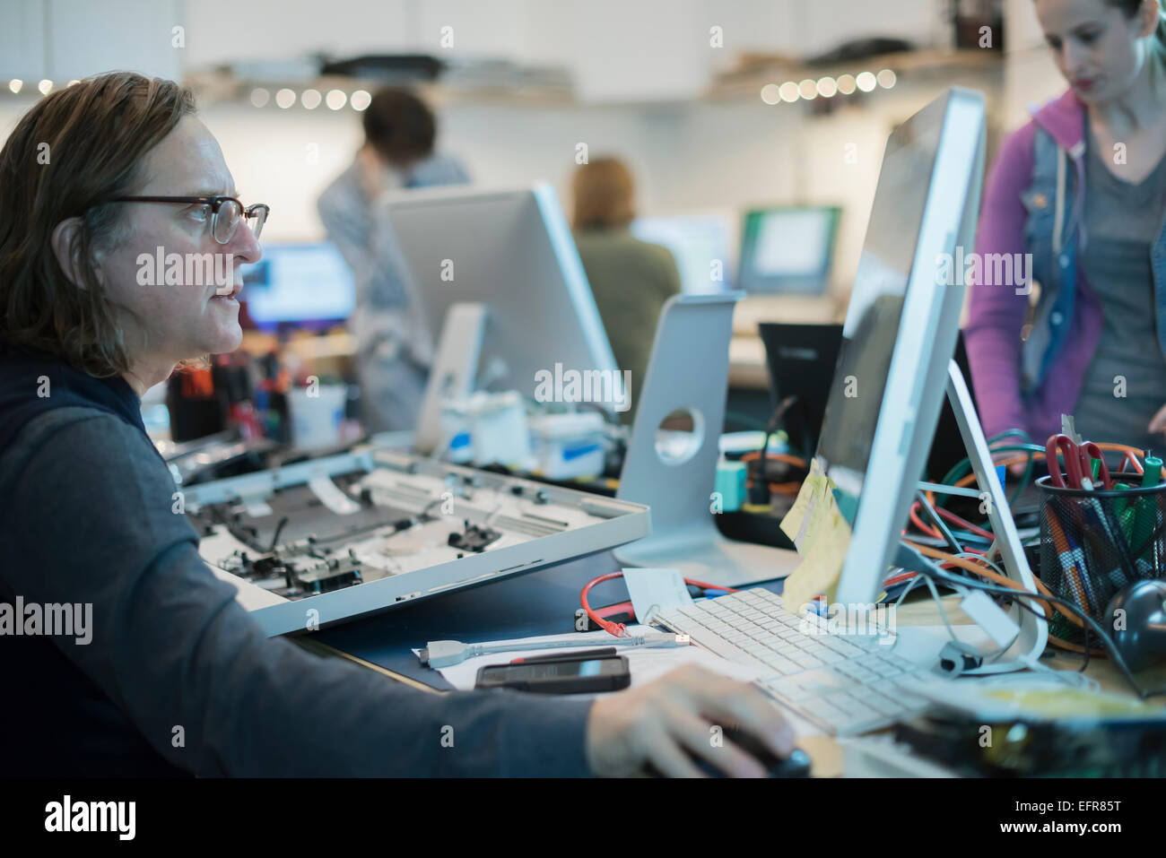 A man seated at a computer, looking at the screen. Computer repair shop ...