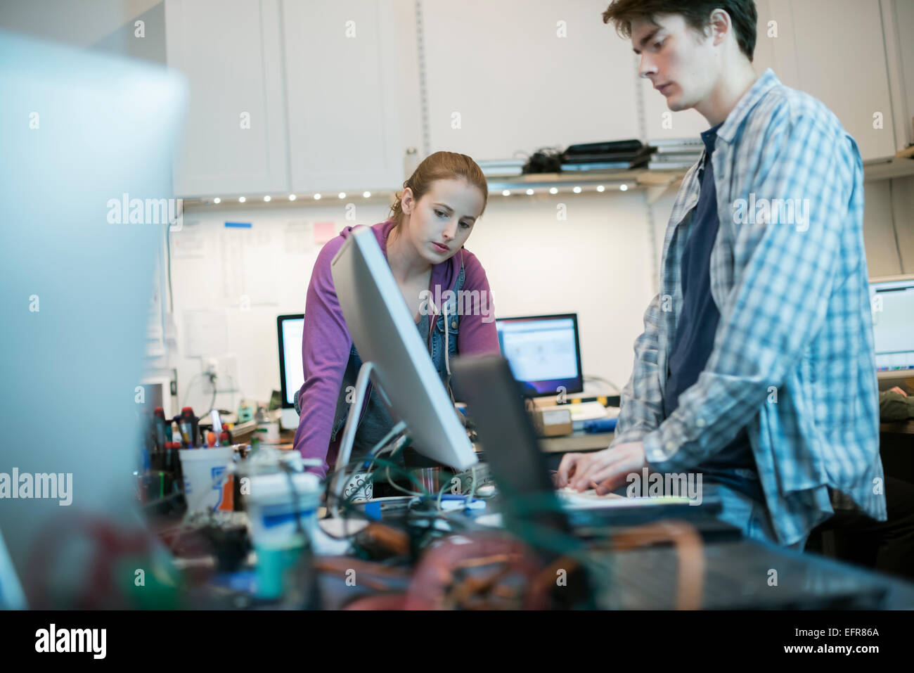 Two people, a man and woman standing at the counter in a computer ...