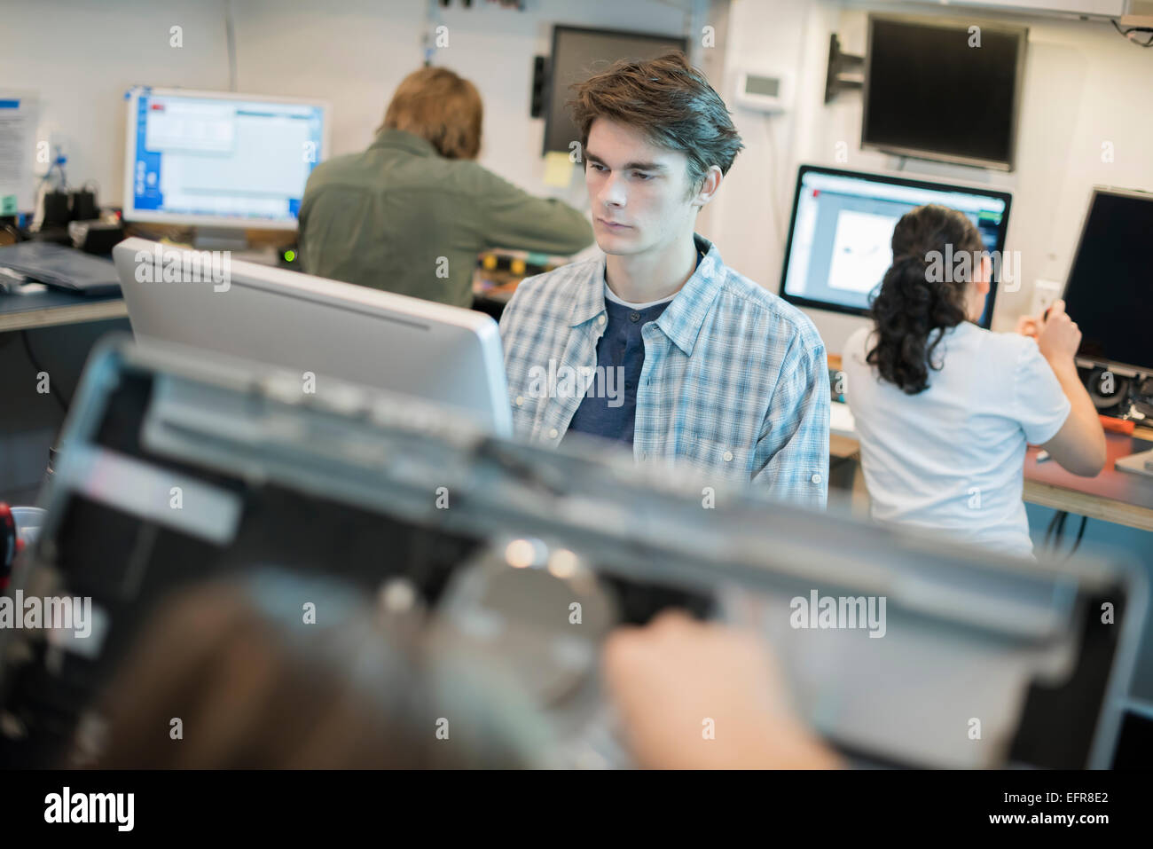 A man seated at a computer, in a repair shop Stock Photo - Alamy