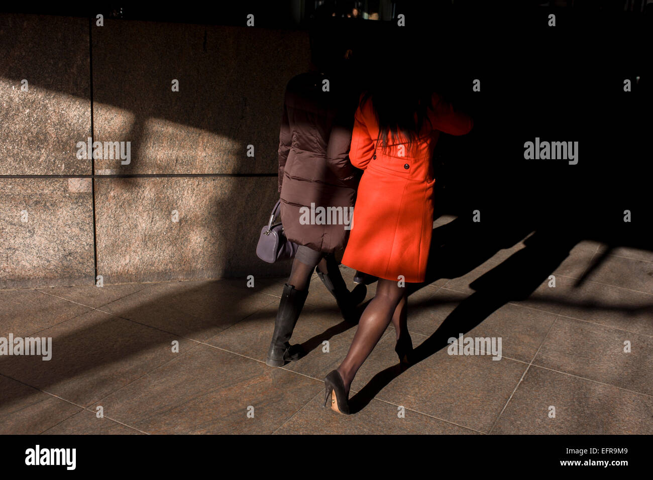 Women walk into dark shadows in Broadgate in the City of London Stock ...