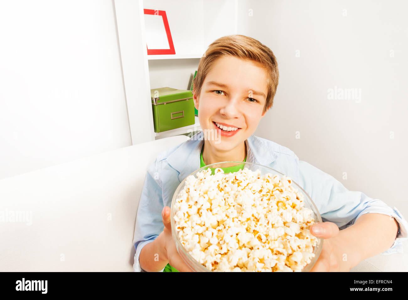 Happy boy with big popcorn bowl on white sofa Stock Photo - Alamy