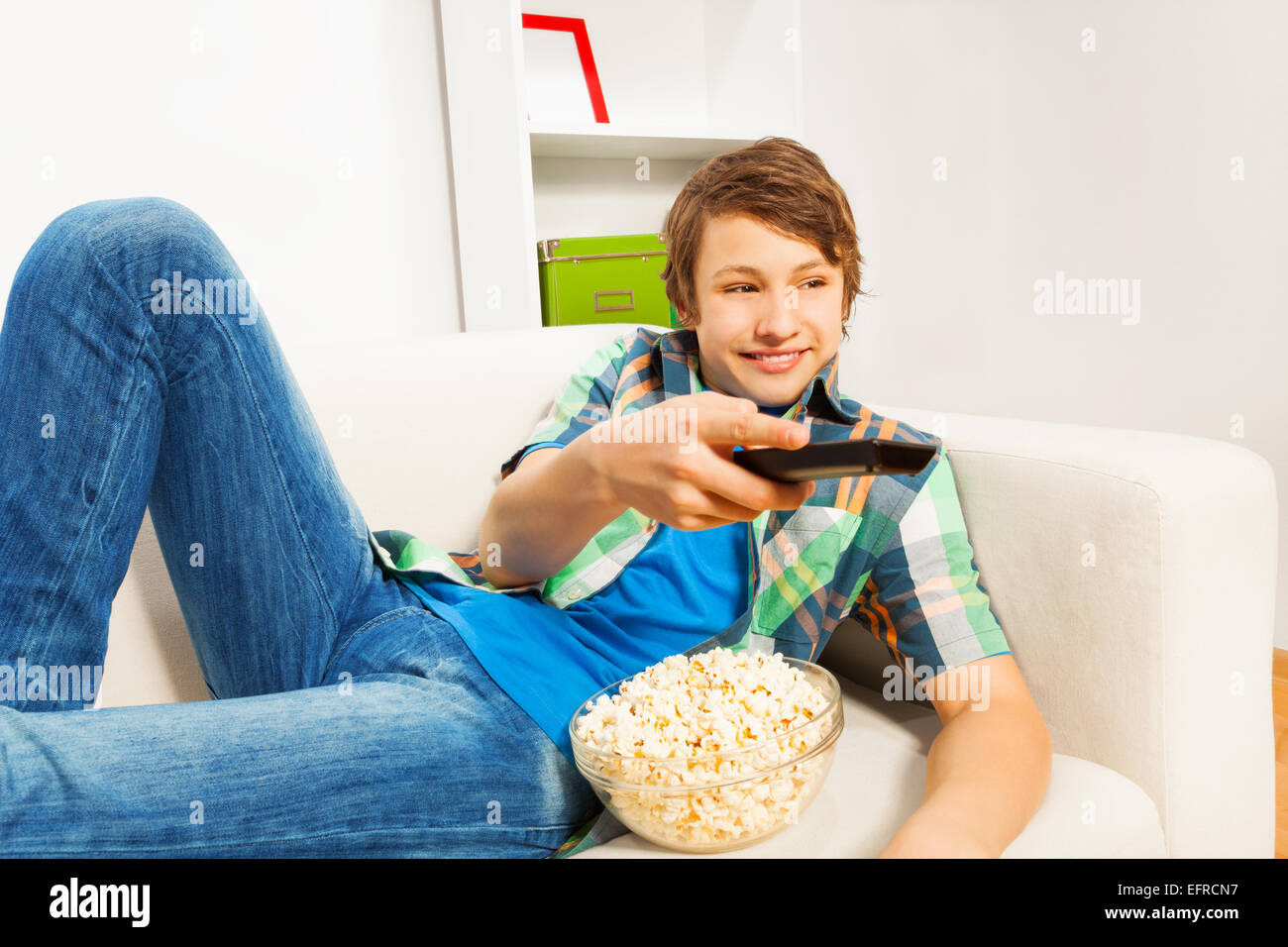 Happy boy with popcorn relaxing on white sofa Stock Photo - Alamy