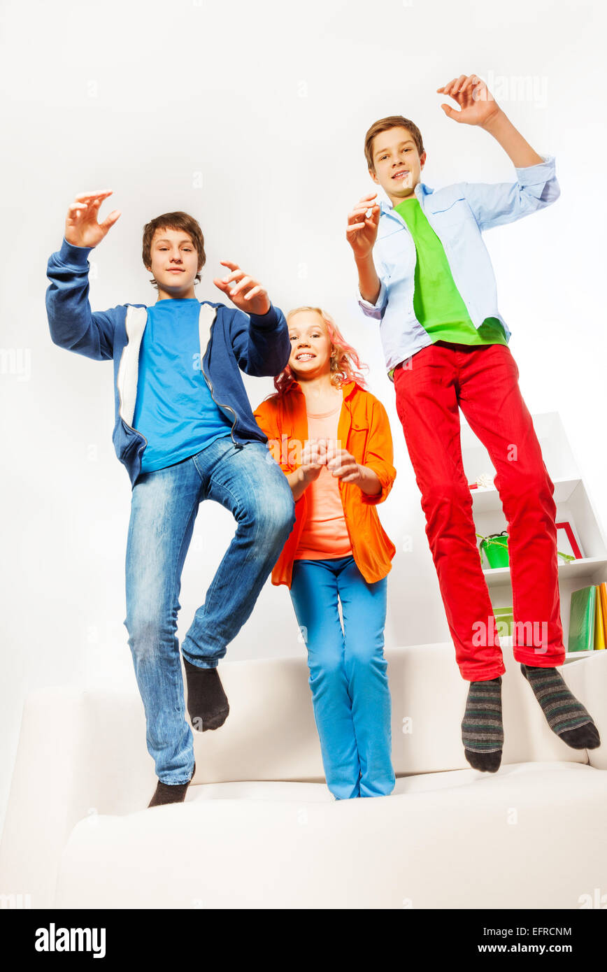 Three happy teenagers jumping on white sofa Stock Photo - Alamy