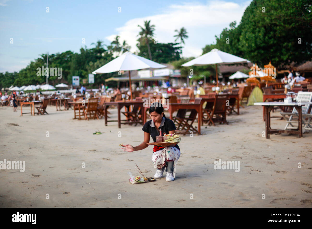 Young woman giving religious offerings at beach in Bali, Indonesia ...