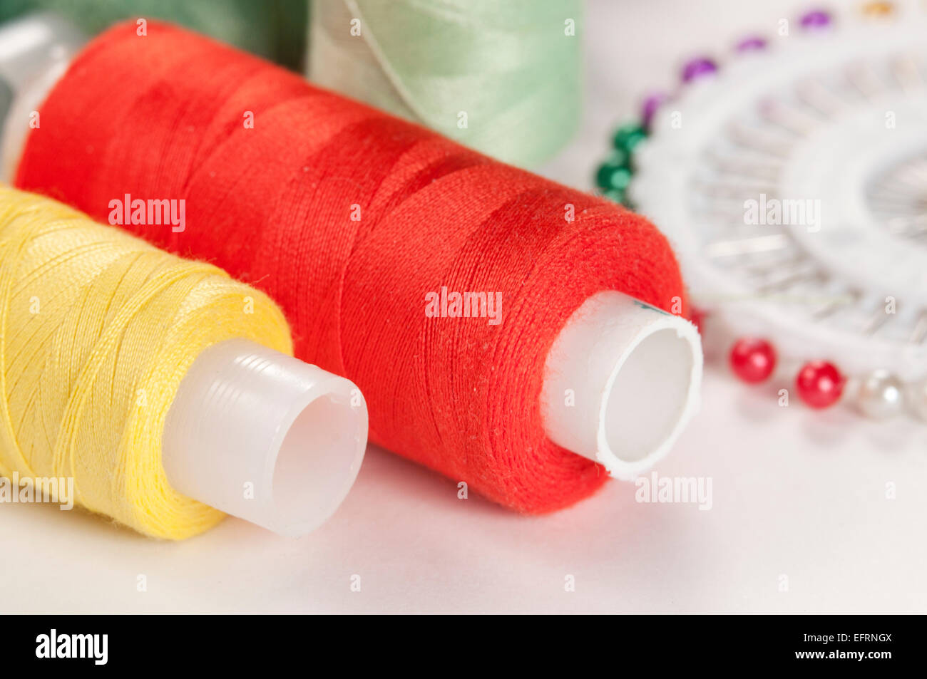 Sewing strings and needles on a light background Stock Photo - Alamy
