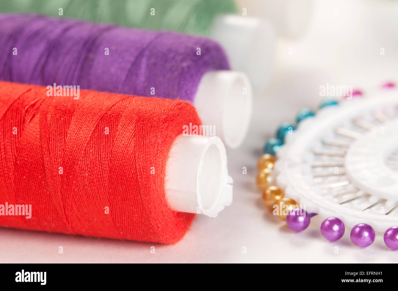 Sewing strings and needles on a light background Stock Photo - Alamy