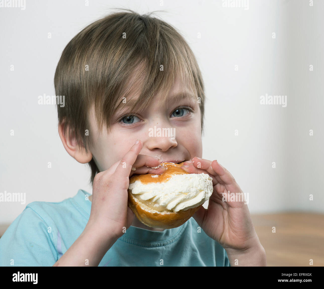 Young boy eating a tasty cream bun Stock Photo - Alamy