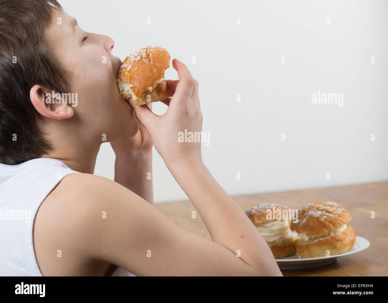 Young boy munching on a cream bun Stock Photo - Alamy