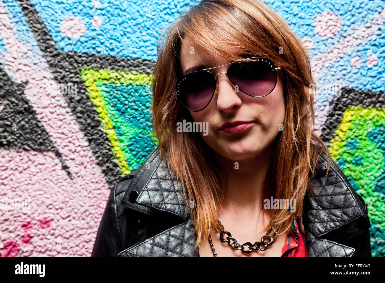 Stylish fashionable girl posing against colorful graffiti wall. Fashion ...