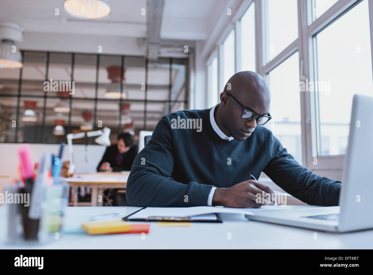 African male executive taking notes. Young businessman working at his ...